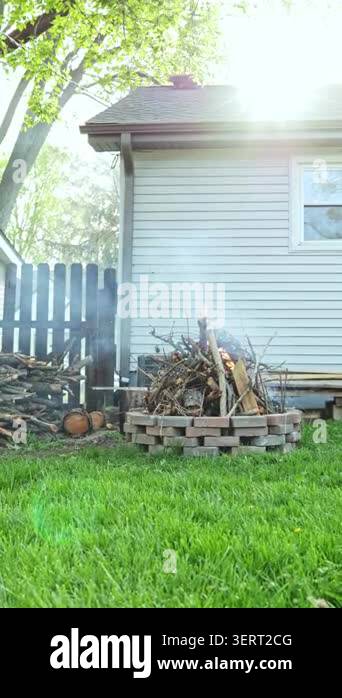 A wood pile sits beside a house with smoke coming from a fire. The sun ...