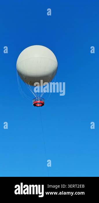 A hot air balloon rises high above the city, suspended by its basket ...