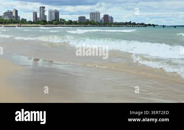 Waves roll onto the sand at a beach where people walk and enjoy the ...