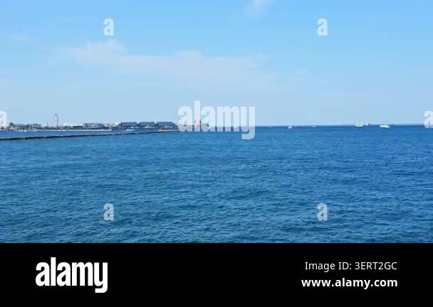 Boats are moving across the water on a clear day. Buildings sit along ...