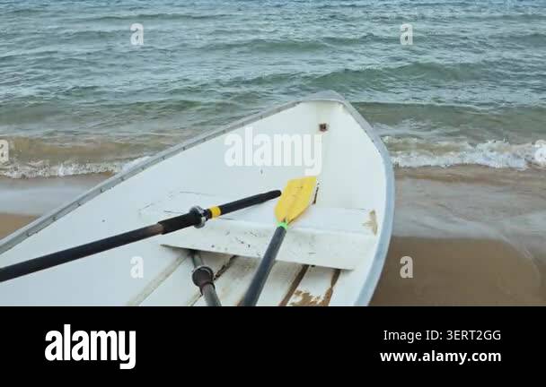 A small boat rests on the sandy beach as waves flow in and out. The sun ...