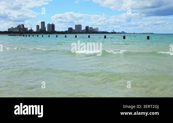 People enjoy the beach as the sun shines. The water reflects the tall ...