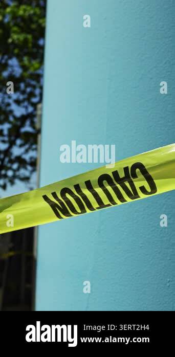 A yellow caution tape is stretched across a blue wall in a park area ...