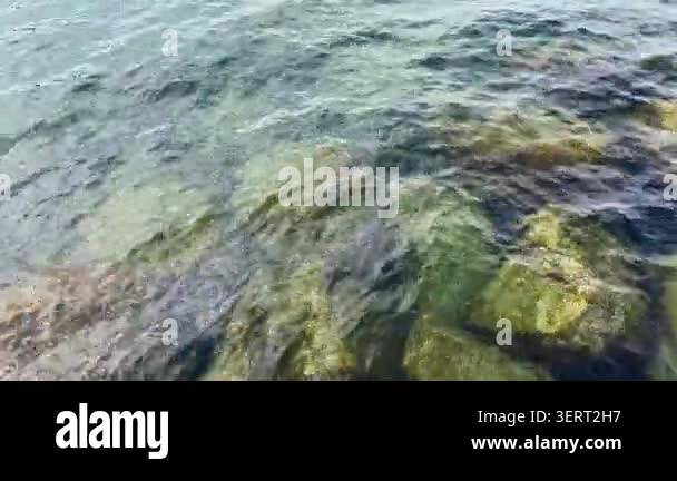 Water moves gently over rocks submerged in the lake during the ...