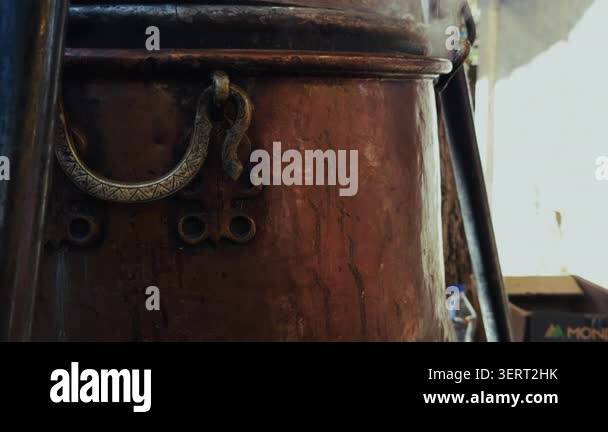 Food boils inside a traditional copper pot outdoors, with rising steam ...