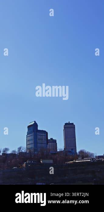 Tall buildings rise against a bright blue sky with a thin white ...