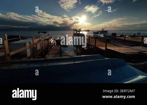 Fishing boats resting on calm sea at dusk as sunlight shimmers across ...