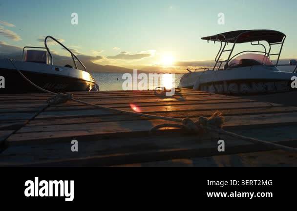 Warm evening light reflecting on a wooden dock between fishing boats ...