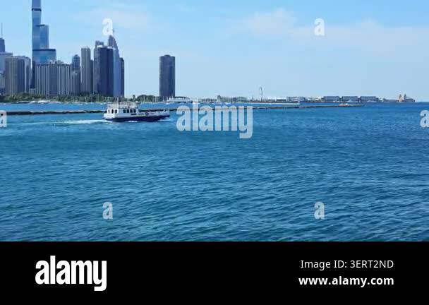 A boat moves across the water in Chicago with buildings in the ...