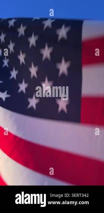 Vertical Screen: USA Flag waves in soft focus against clear blue sky in ...