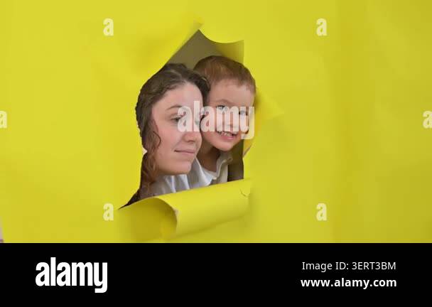 Cheerful young mother with curly brown hair and her toddler son wearing ...