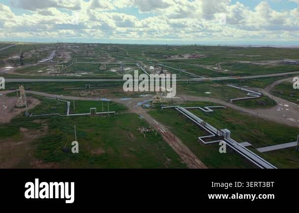 Aerial view pipelines snaking across grassland with scattered pumpjacks ...