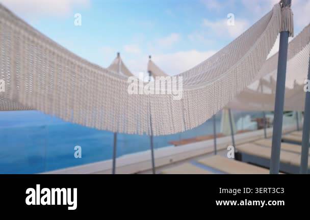 Elegant white woven hammock with decorative fringe sways gently at a ...