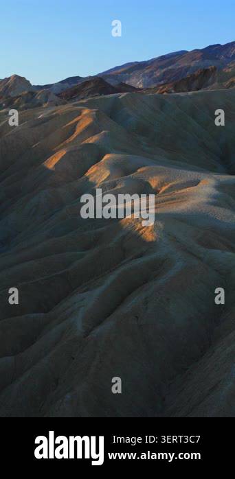 Vertical Screen: Golden hour sunlight illuminates ridges of eroded ...