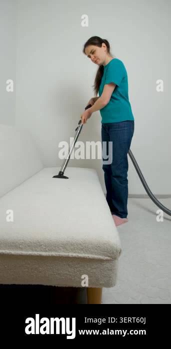 Full length profile of woman vacuuming white sofa at home Stock Video ...