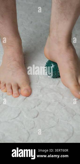 Man massaging myofascial trigger points on foot with green spiky ball ...