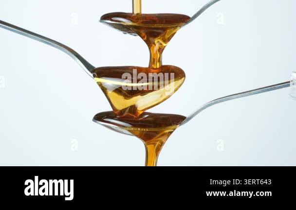 Abstract art of maple syrup flowing over spoons, slow motion on white ...