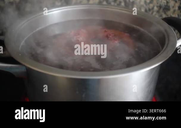 Close up shot of a whole octopus boiling in a stainless steel pot with ...