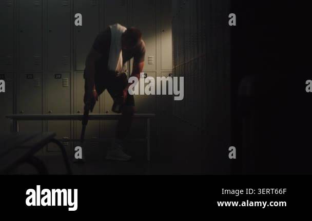 Man Heavily Sits Down on Bench, Leaning Back Against Metal Lockers For ...