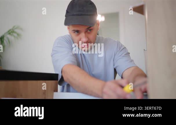 Young man wearing cap uses screwdriver from toolbox to perform ...