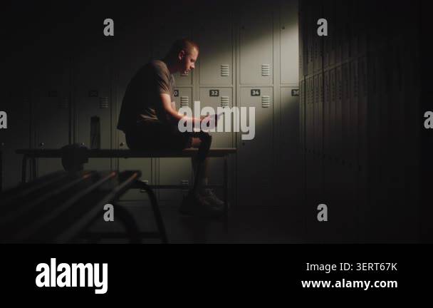 Athlete with Limb Loss Sits on Bench in Dressing Room, Typing Message ...