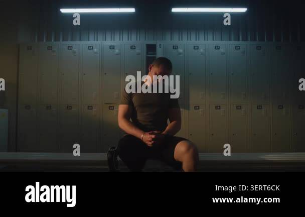 Young Man with Prosthetic Leg Sits on Bench in Dimly Lit Locker Room ...