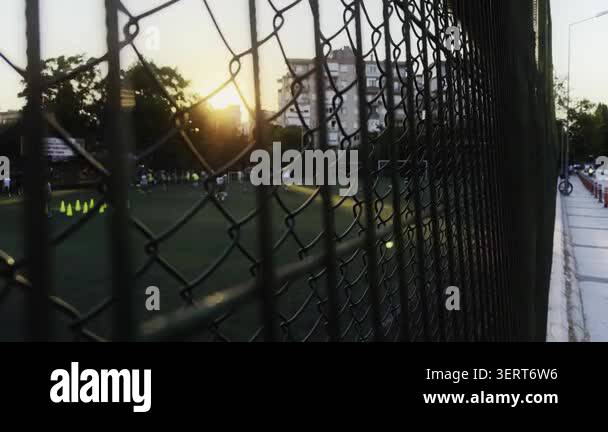 Children Practicing Football Behind a Wire Fence at Sunset Light Stock ...