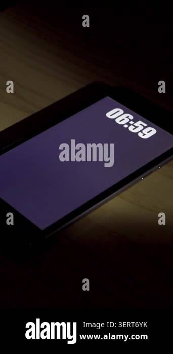 Smartphone alarm clock app rings for wake up, screen shows at bedroom ...