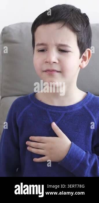 Sneezing boy suffering from flu or allergy symptoms sitting on a sofa ...