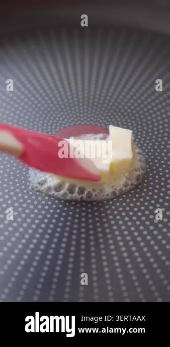 Butter melts and bubbles in frying pan while spatula moves it across ...