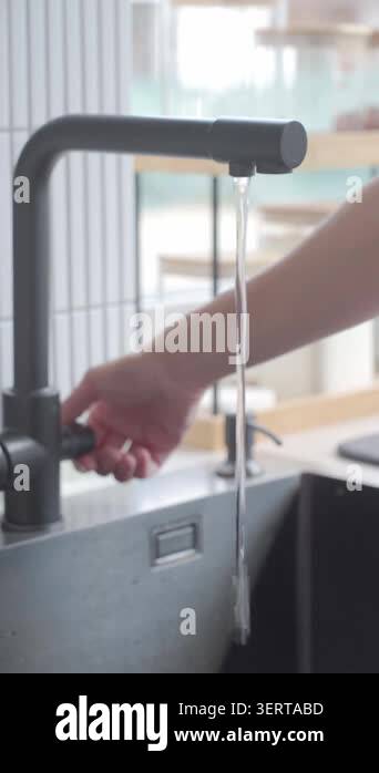 Person turns on black faucet with running water. Hand washing at ...