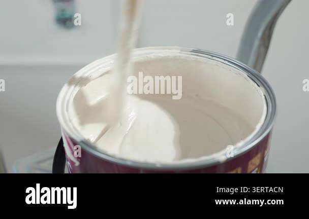 Stirring white paint in an open paint can with a wooden stick. Concept ...