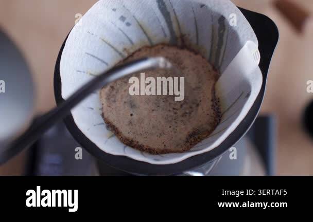 Hot water pours over ground coffee in a paper filter, creating coffee ...
