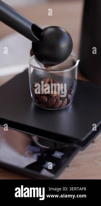 Weighing coffee beans on digital scale, black scoop adds roasted beans ...