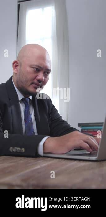 Thoughtful Businessman Working on a Laptop in an Office While Holding ...