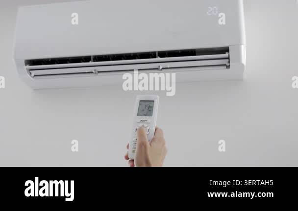 Person adjusts air conditioner temperature with a remote control in a ...