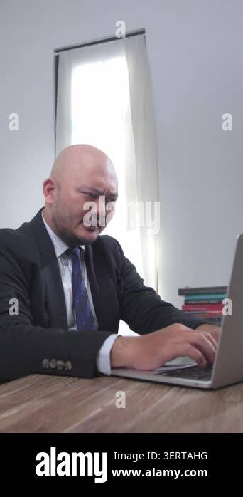 Tired Businessman Working on a Laptop in the Office While Holding the ...