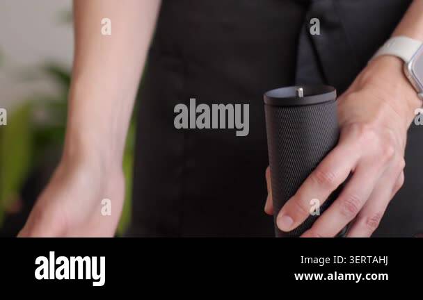 Hands pour coffee beans from a glass cup into a manual coffee grinder ...