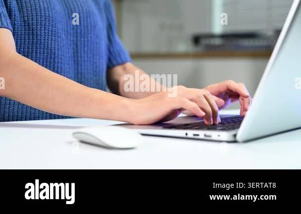 Close-up of a person's hands typing on a laptop keyboard with a ...