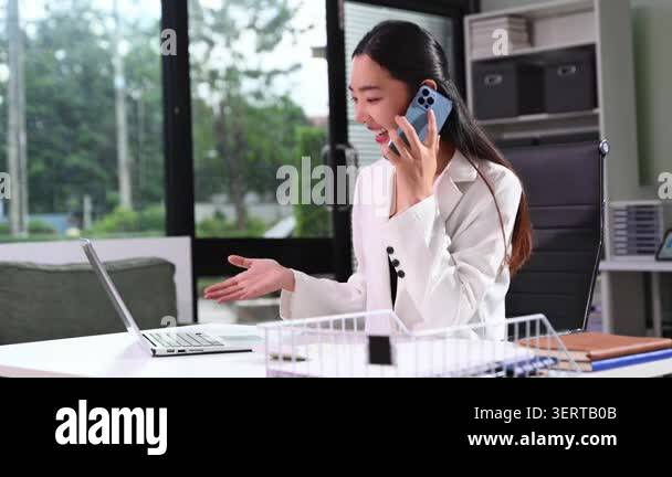 A woman in a white blazer is talking on her phone and typing on a ...