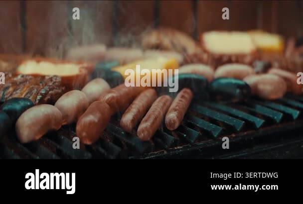 Grilled sausages sizzle on a metal grill. Smoke rises from the cooking ...