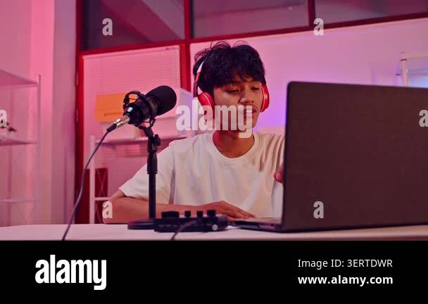 Cheerful male content creator wearing red headphone read live chat on ...