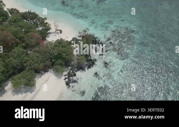 Slow top down aerial hovering over a rocky mangrove islet edge with ...