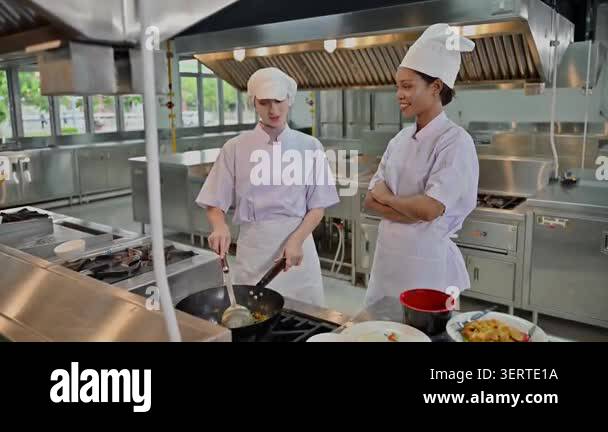 Professional senior female chef wearing white uniform teach young ...