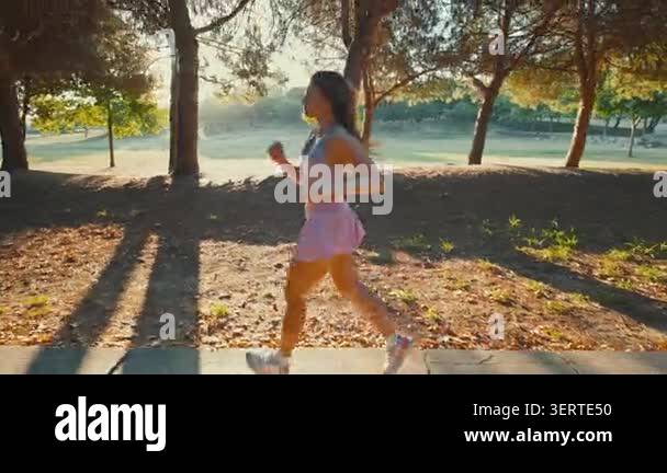 Young athletic woman running on a path in a park during a beautiful ...