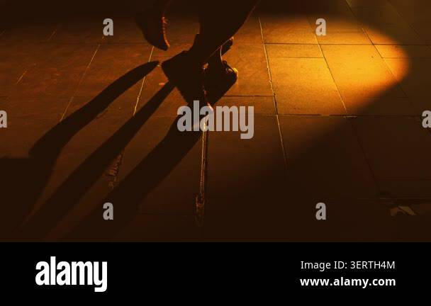 A person stands in a dimly lit area, with light shining on their feet ...