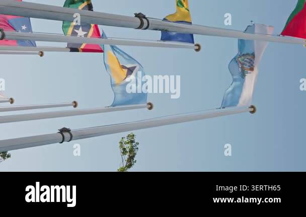 Different country flags are flying on tall poles in a public area. The ...