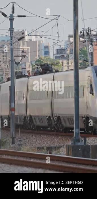 A train travels on tracks in an urban area. Buildings and wires are ...