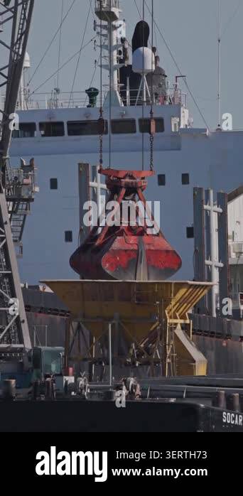 Lifting equipment moves heavy cargo from a large ship to the dock ...