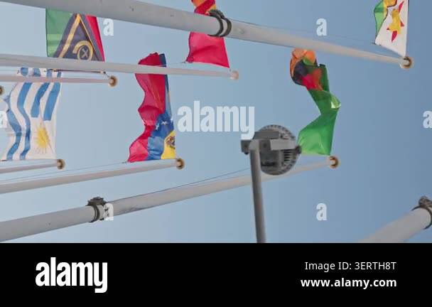 Various flags from different nations wave in the wind under a clear ...